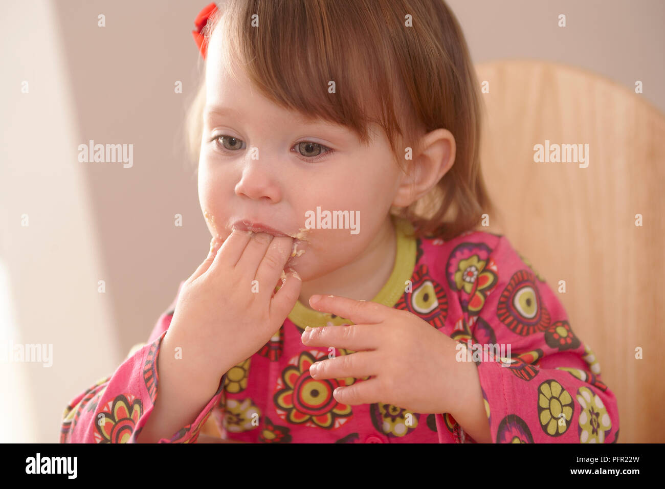 Young girl eating finger food with three fingers in mouth, close-up ...
