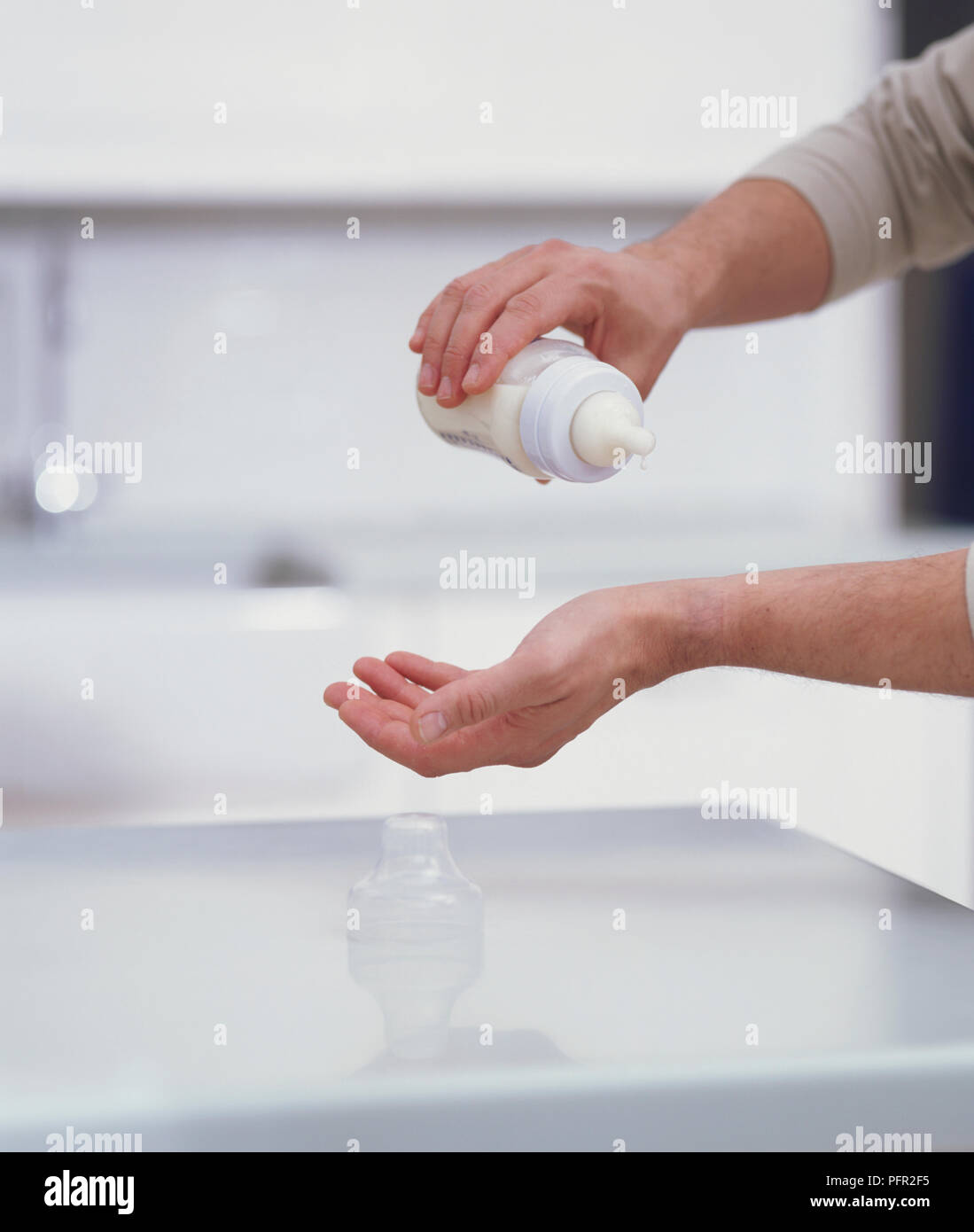 Man testing milk temperature, dropping milk from bottle onto wrist ...