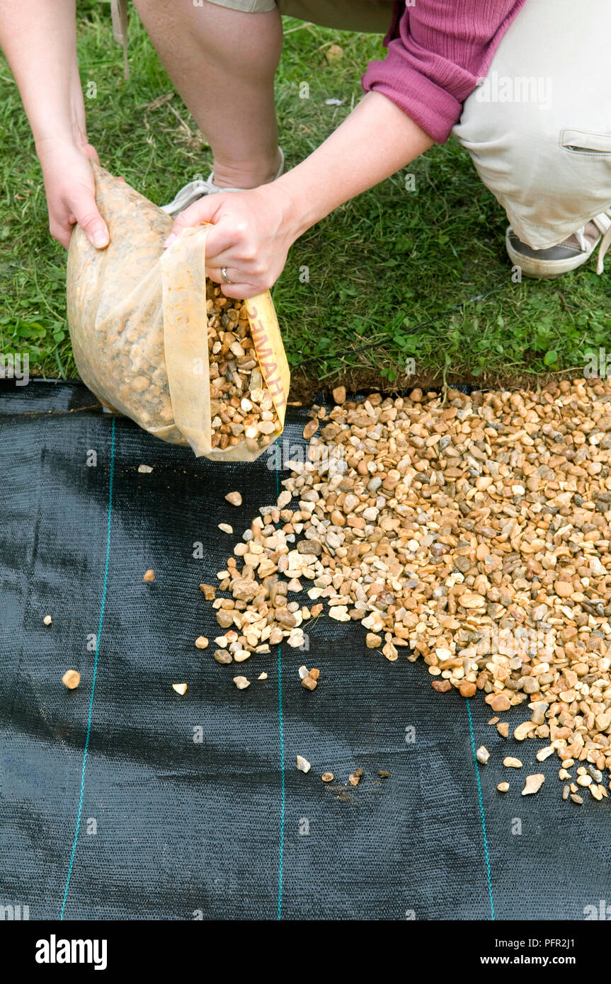 Pouring gravel over permeable membrane to form base of a herb path ...