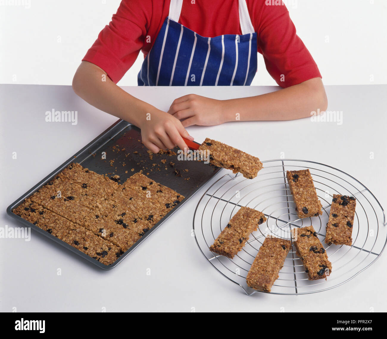 Child placing flapjacks on wire rack to cool Stock Photo - Alamy