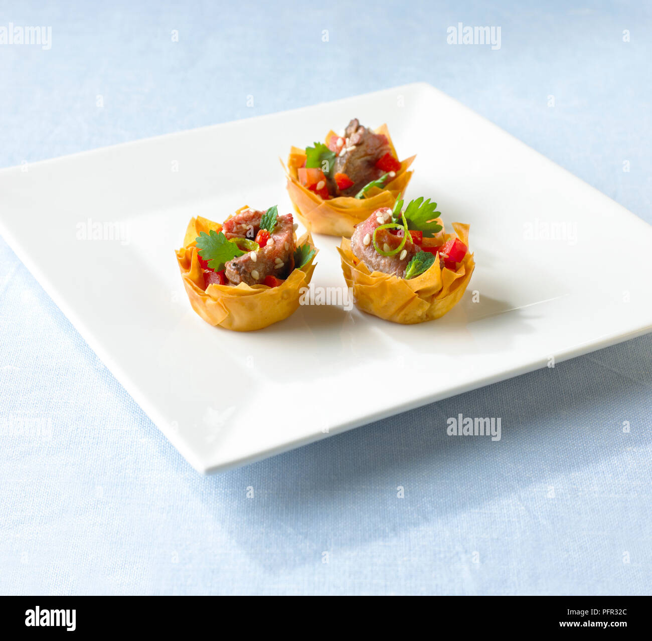 Filo pastry filled with Asian beef salad and garnished with peppers ...