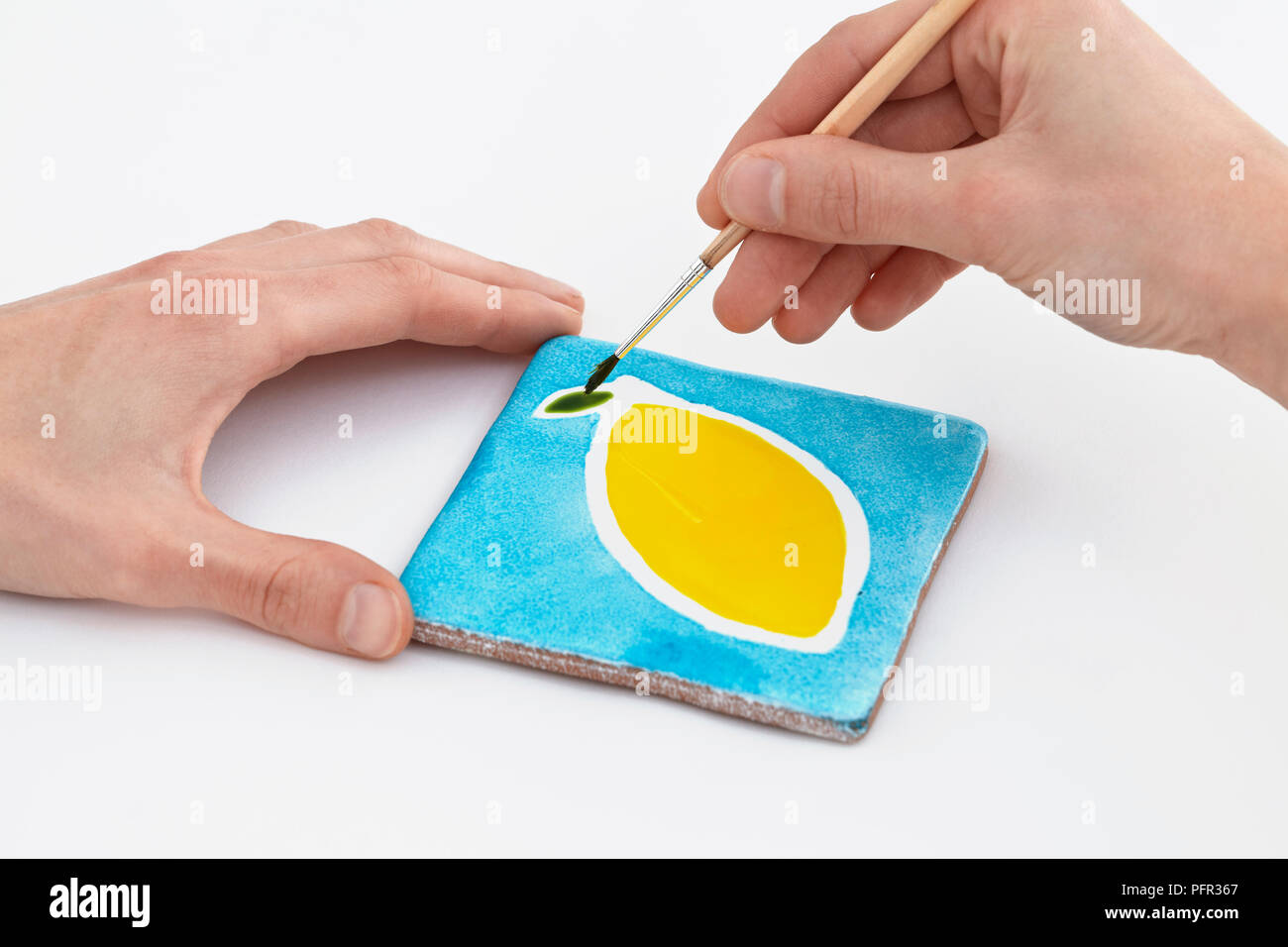 Painting a lemon on an old tile to make a coaster Stock Photo - Alamy