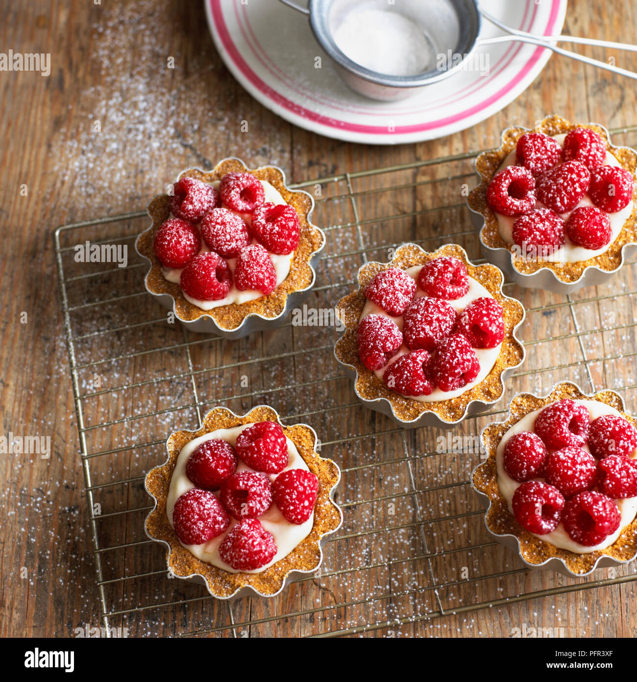 Raspberry tartlets with cream filling and dusted with icing sugar, on ...