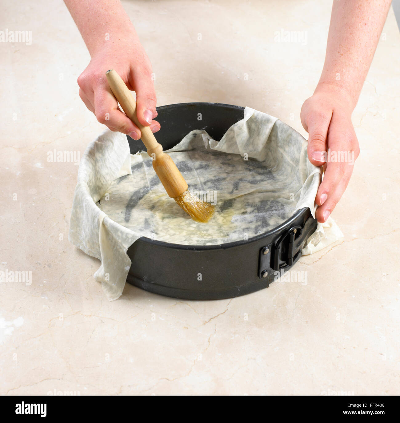 Making filo pie, covering bottom of springform tin with sheet of pastry ...