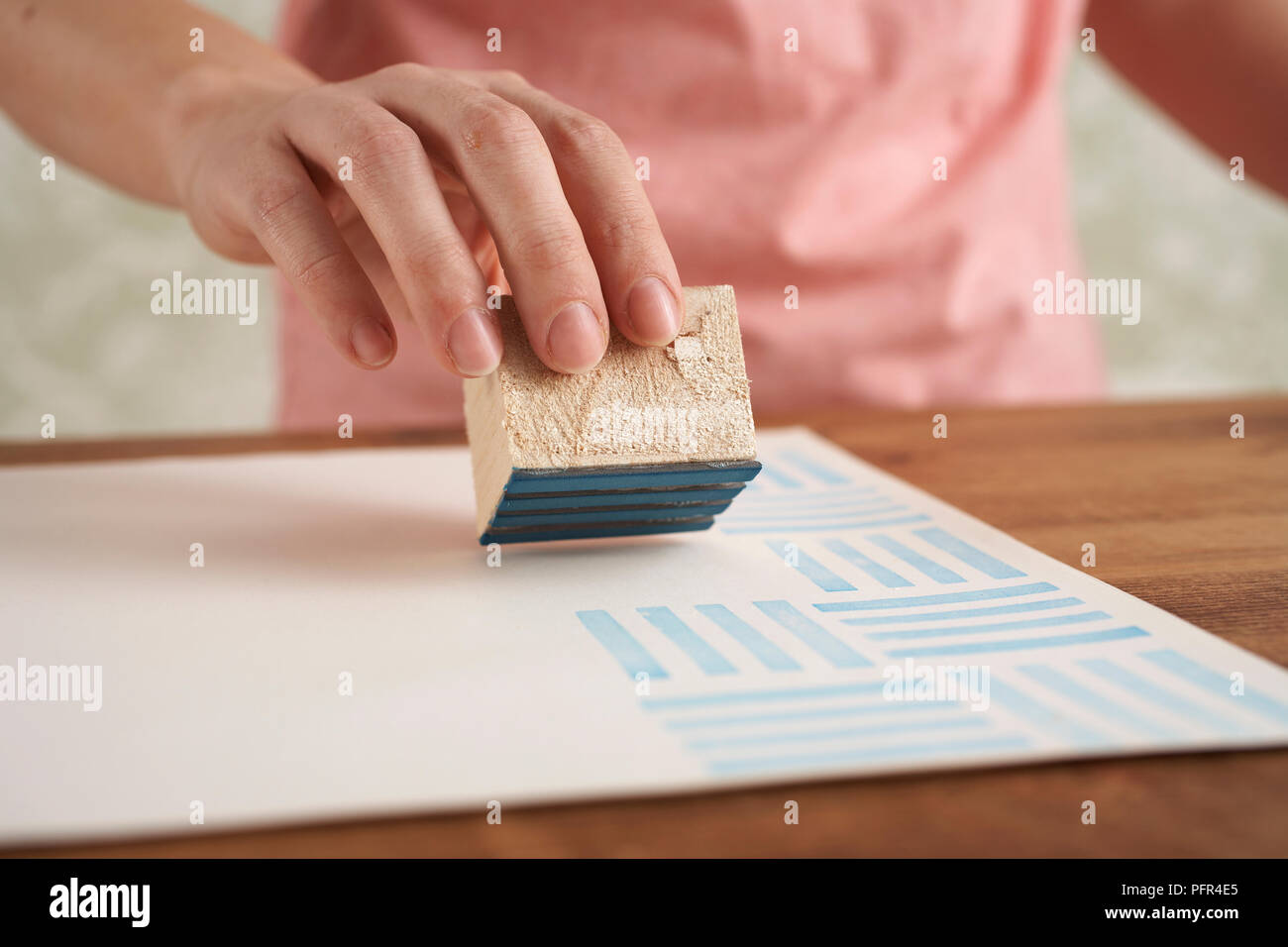 Using stamp to make line pattern on sheet of wrapping paper Stock Photo ...