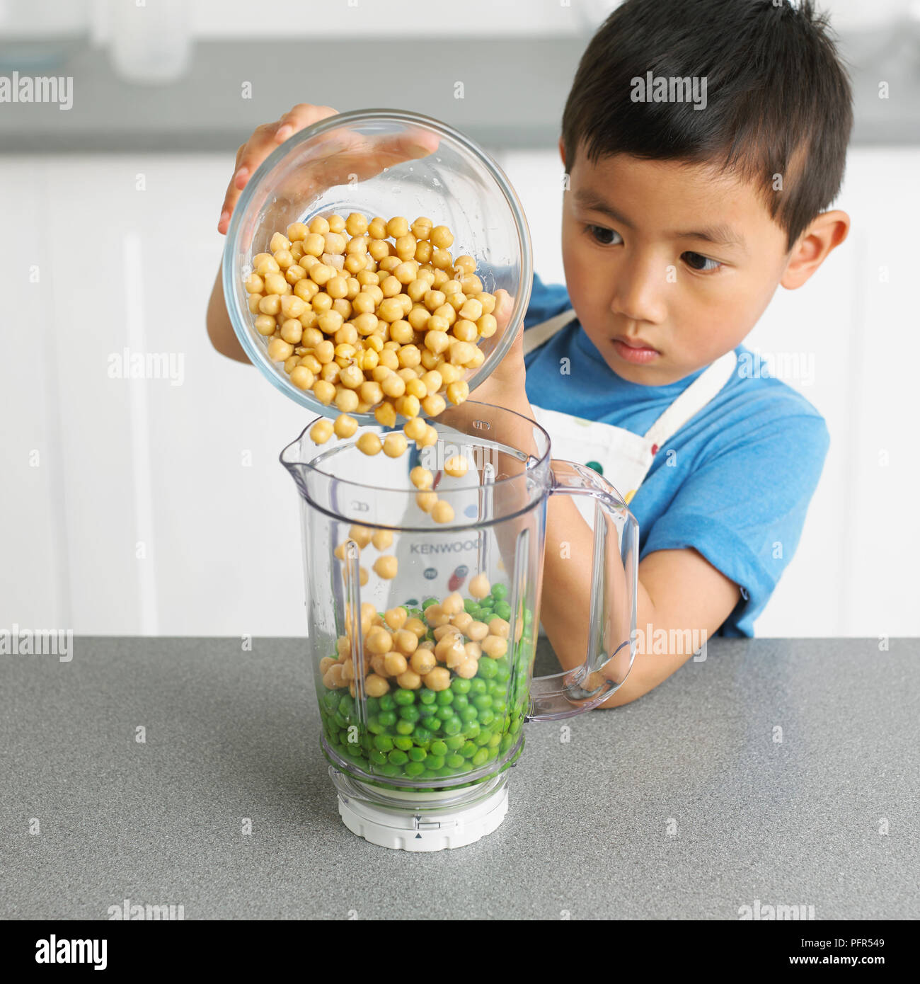 Making pea hummus, Boy pouring chickpeas into jug of peas, 4 years ...
