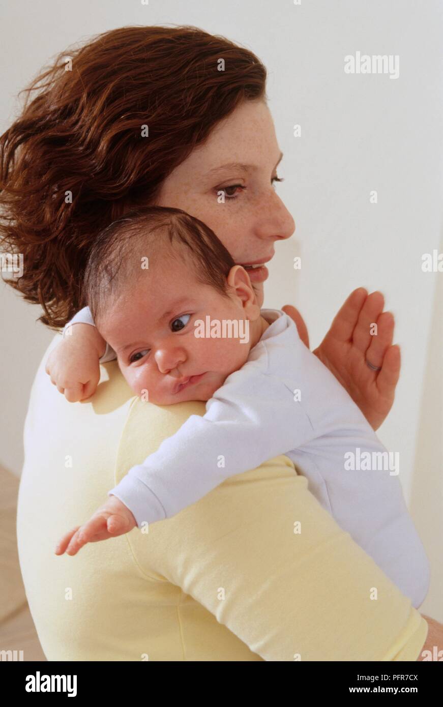 Woman holding baby against shoulder while patting her back Stock Photo ...