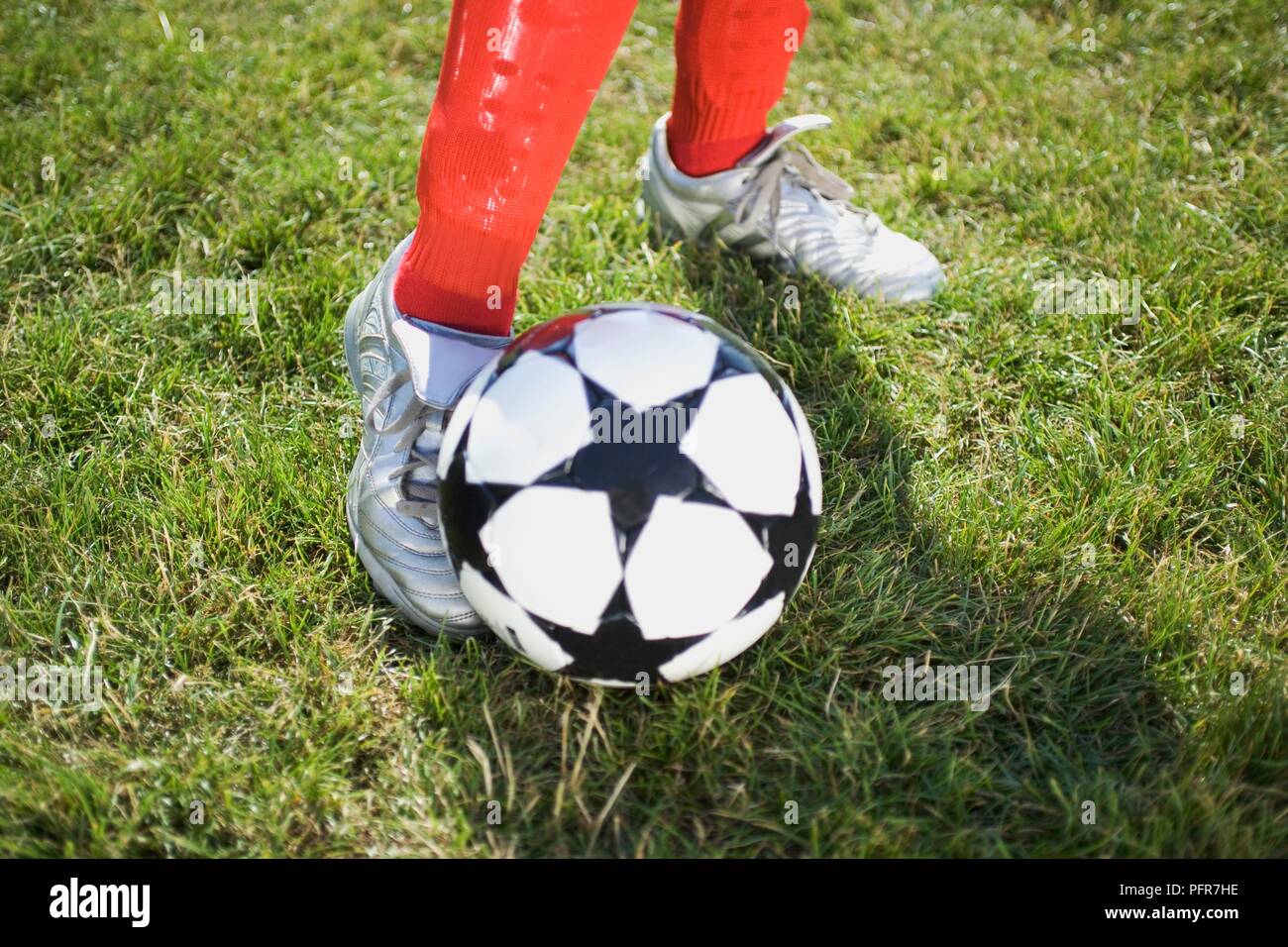 Young football player's foot tucked under a football with star shapes ...