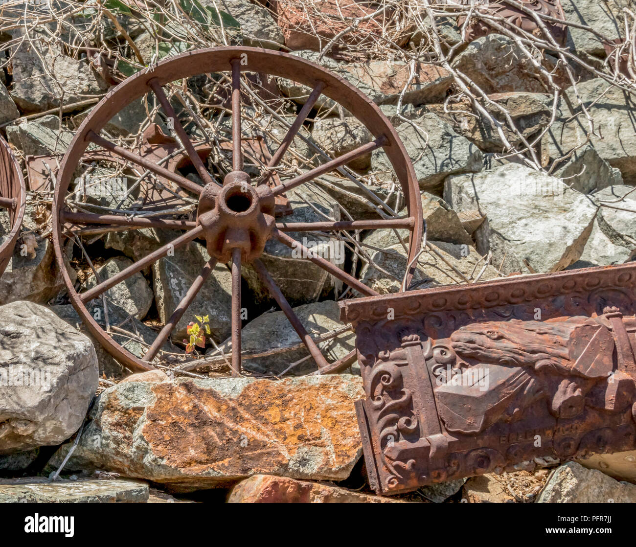 Rusty vintage vehicle wheel and scrap metal on rocks Stock Photo - Alamy