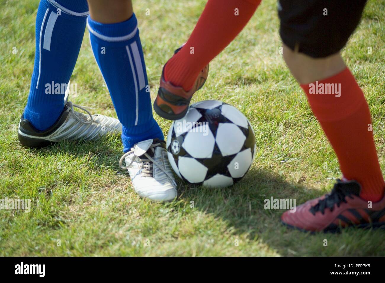 Two young football players placing foot over ball in foul tackle, close ...