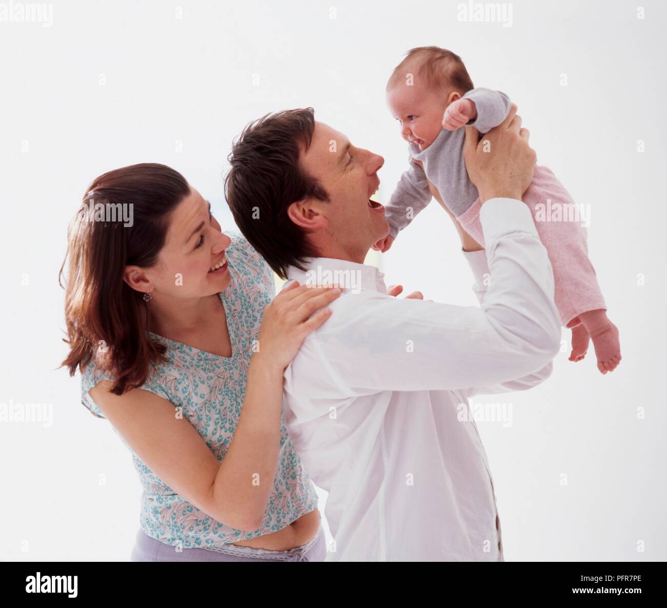 Couple with baby, man raising baby in the air in his hands Stock Photo ...