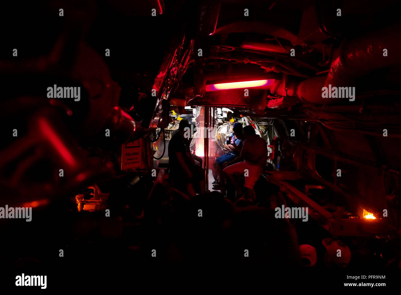 Sailors under red light in a mock attack in the torpedo room of the BAP ...