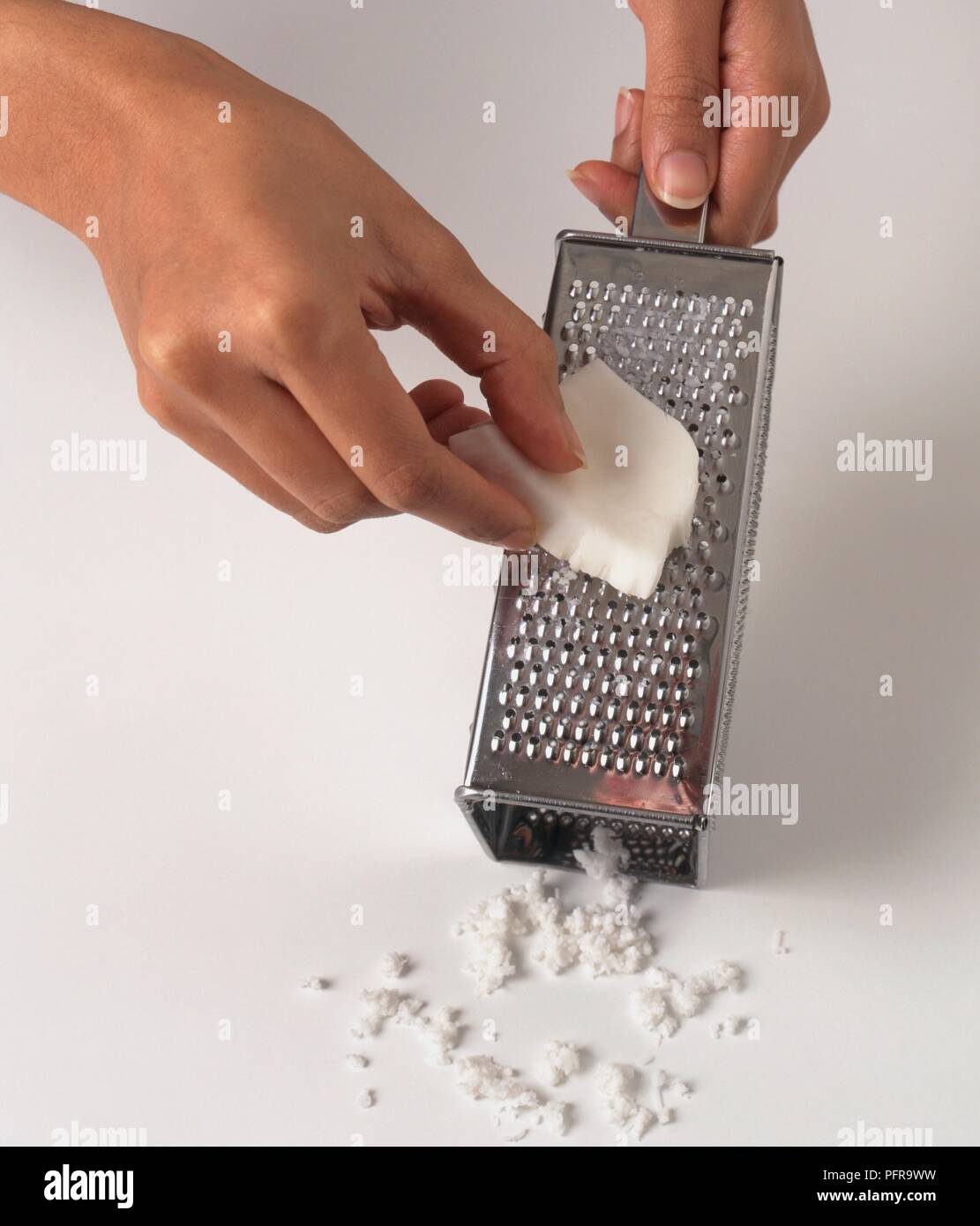 Grating coconut on metal grater Stock Photo - Alamy