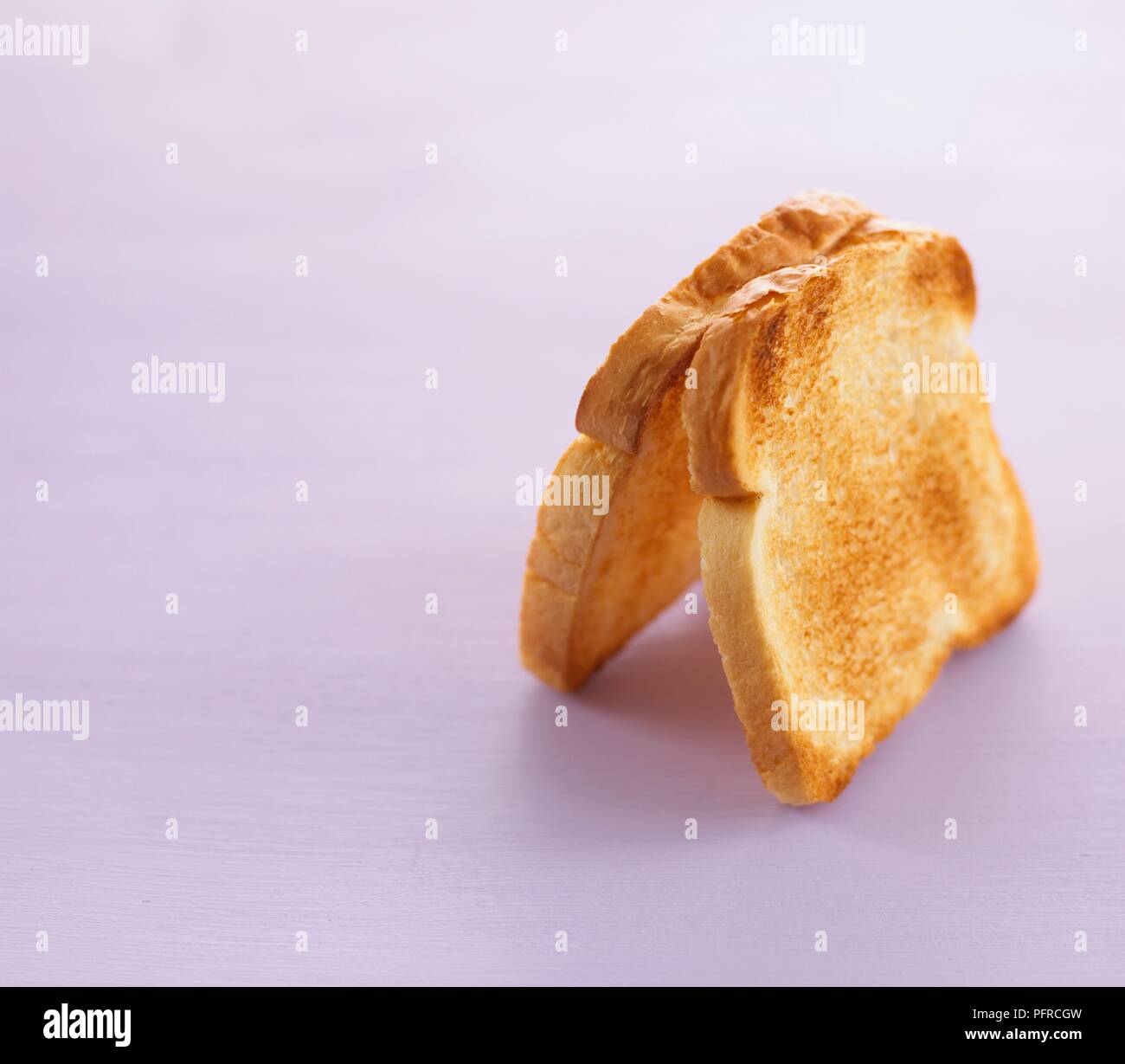 Two slices of white bread toast leaning aginst each other in upright ...