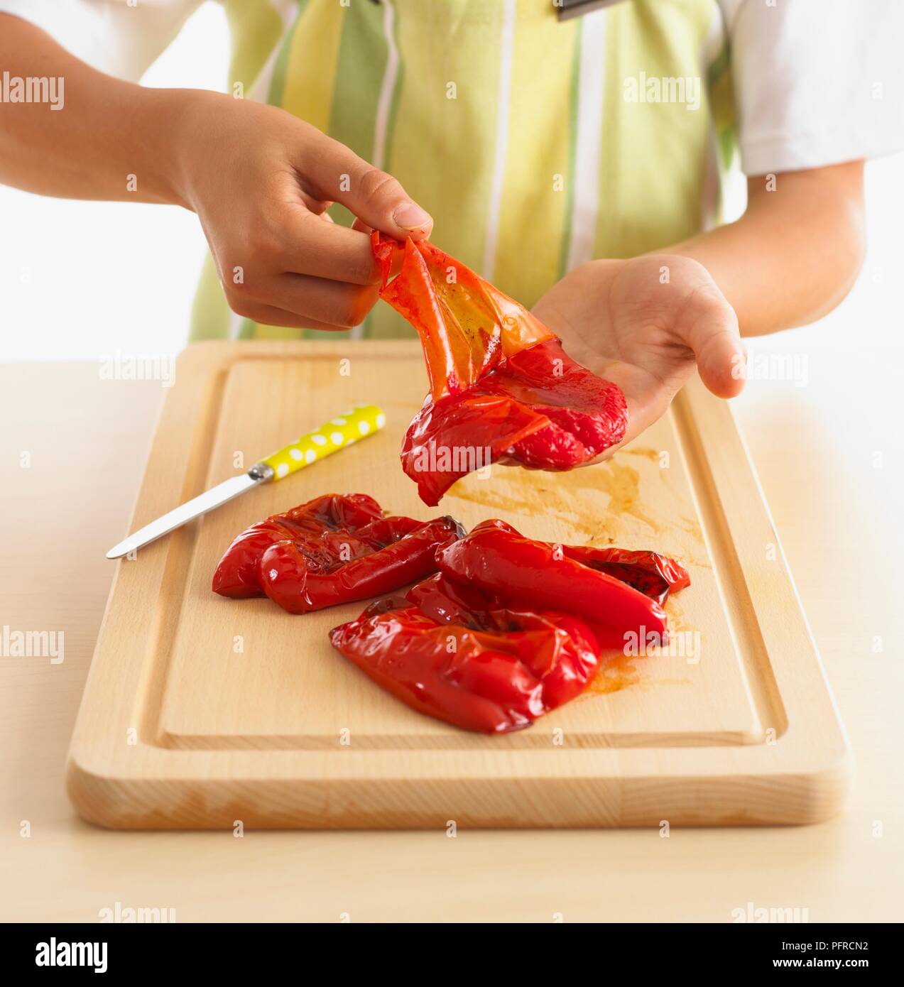 Girl's hands removing the skins from a roasted red pepper, close-up ...