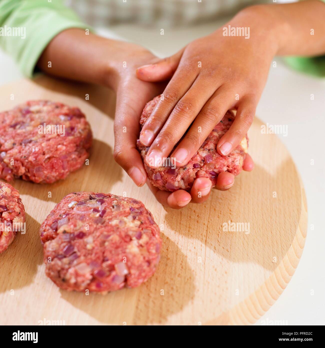 Girl's hands flattening minced beef mixture into burger shape on ...