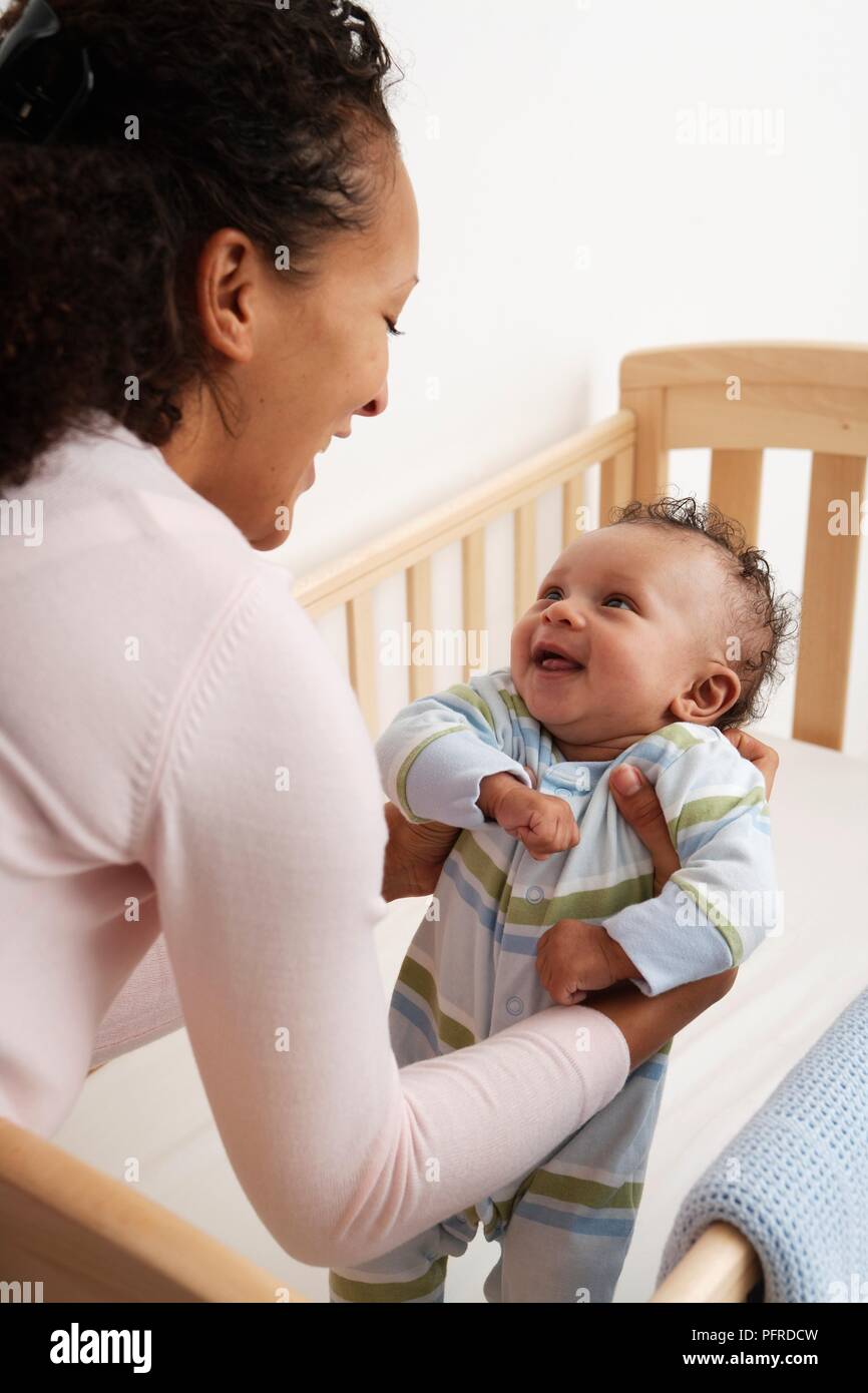 Woman picking up baby boy from cot, close-up Stock Photo - Alamy