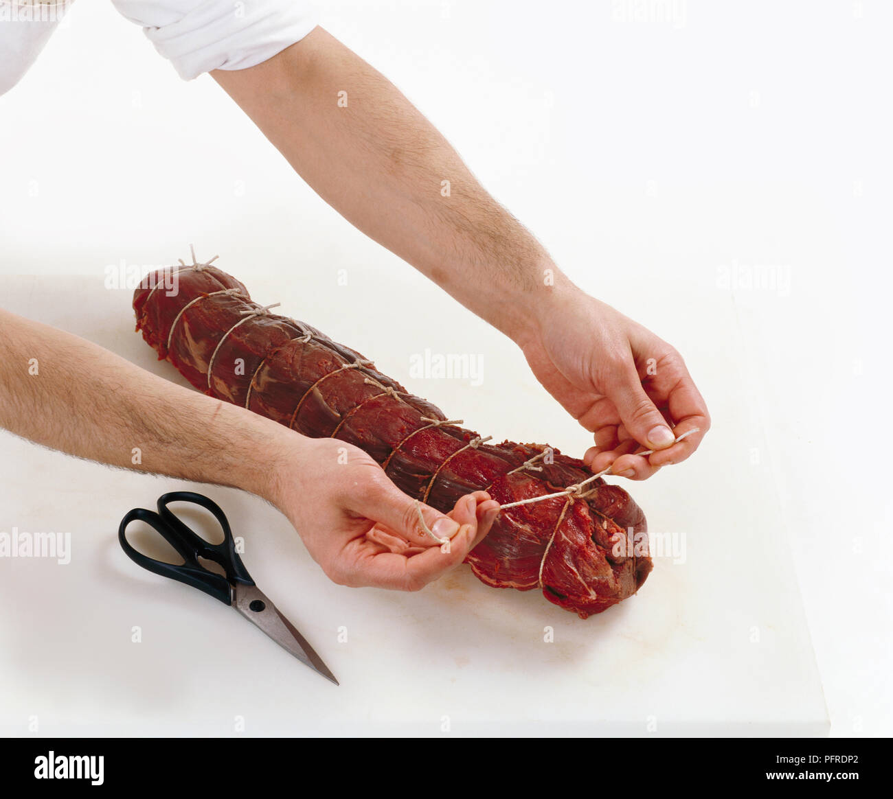 Rolled up red meat being tied with string, close-up Stock Photo - Alamy