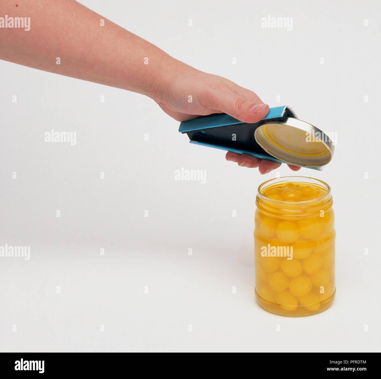 Woman using gripper to remove lid from jar of pickled onions Stock ...
