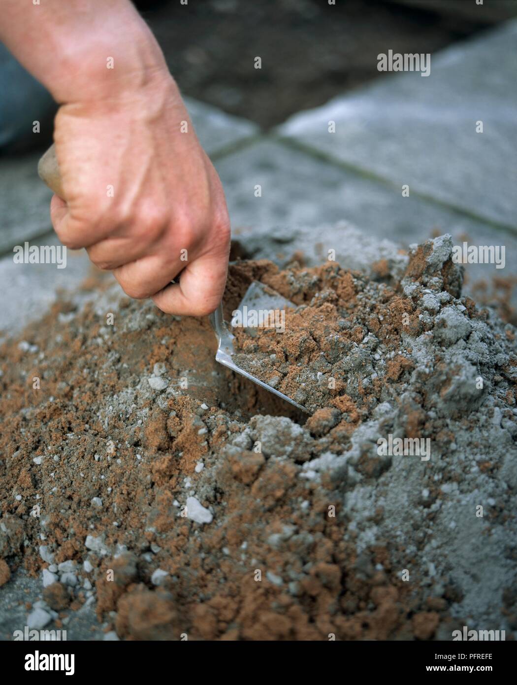 Making dry mortar by mixing three parts of sand to one of cement, close ...