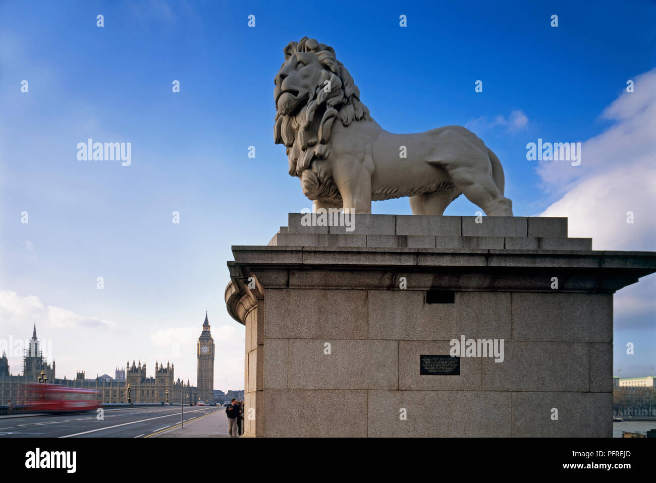 England, London, Westminster Bridge, lion statue with moving bus and ...