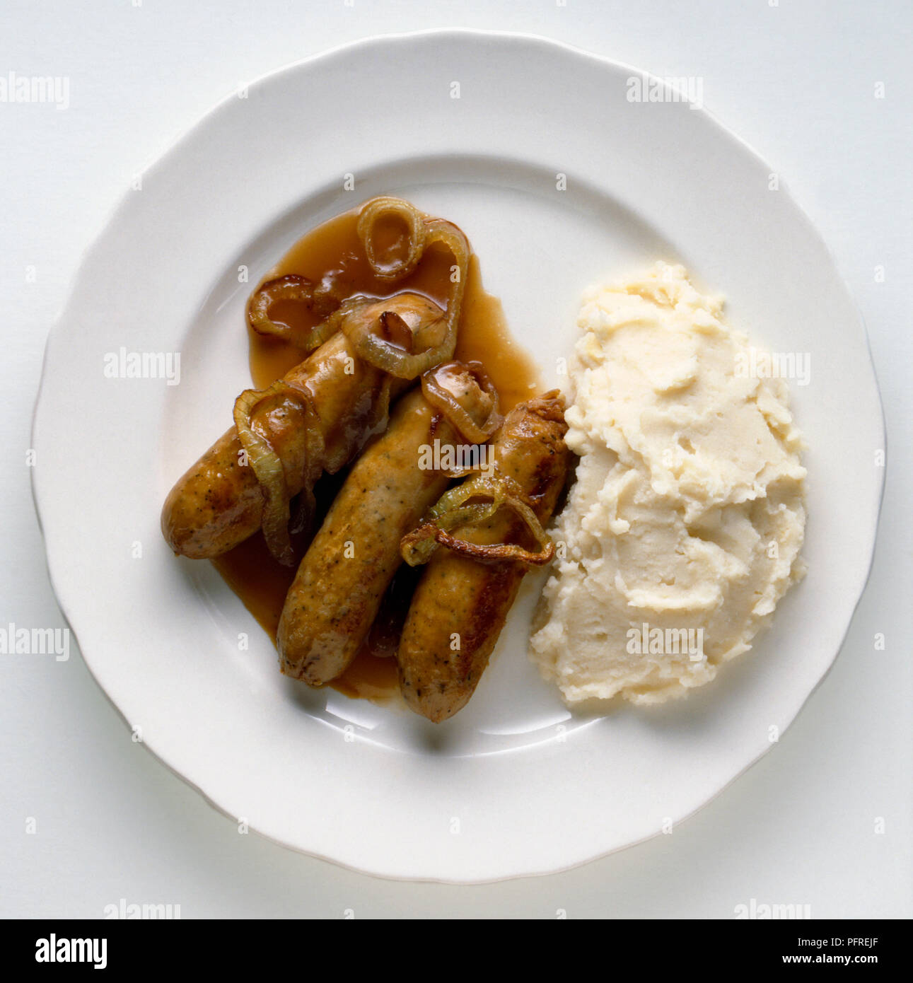 Bangers and mash with onion gravy on white plate Stock Photo - Alamy