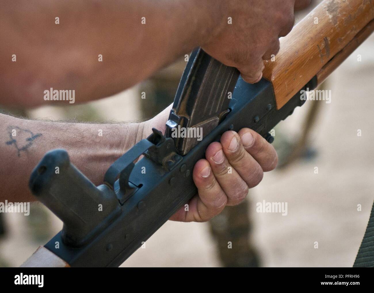 A Syrian Democratic Forces soldier loads a magazine into his AK-47 ...