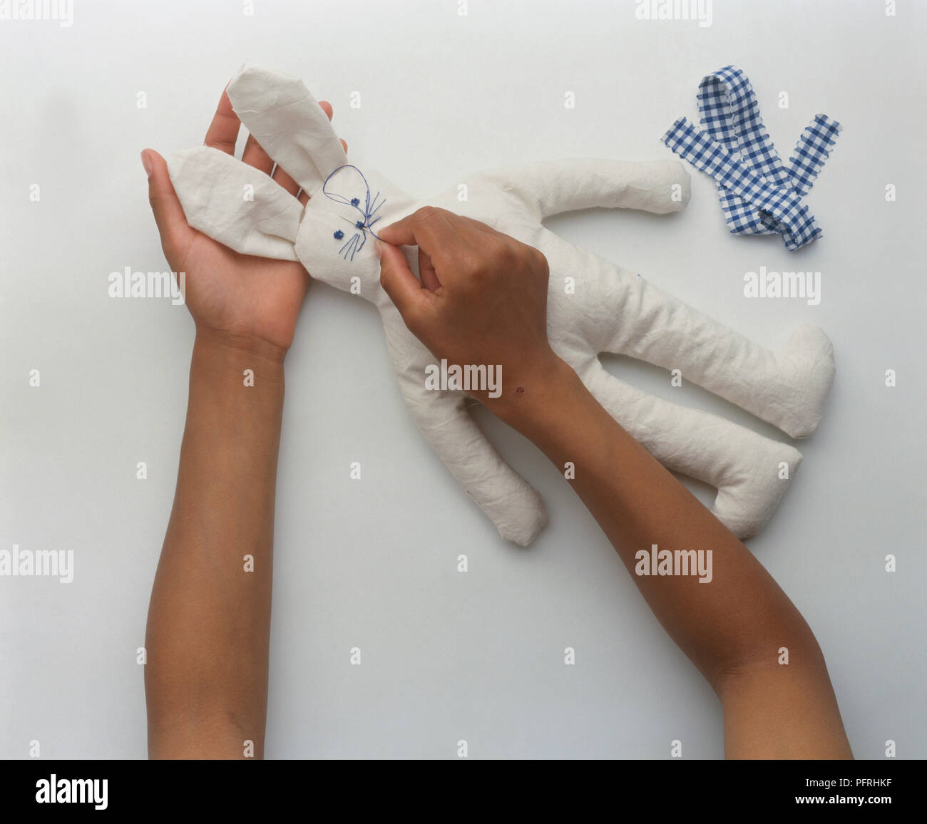 Sewing face on stuffed toy rabbit's face Stock Photo - Alamy