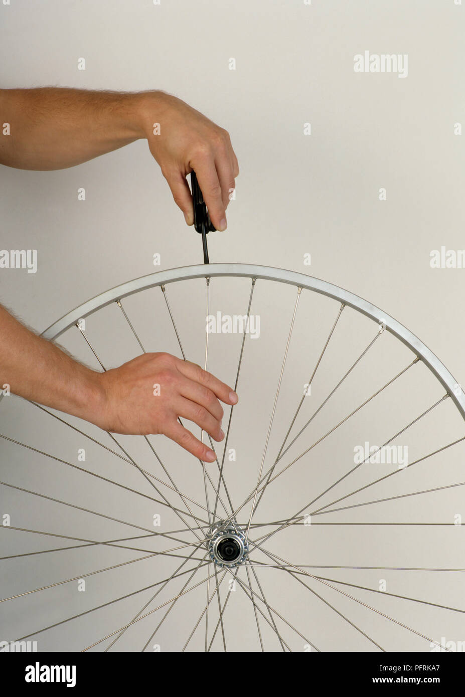 Spoke being threaded through the end of the wheel rim and tightened ...