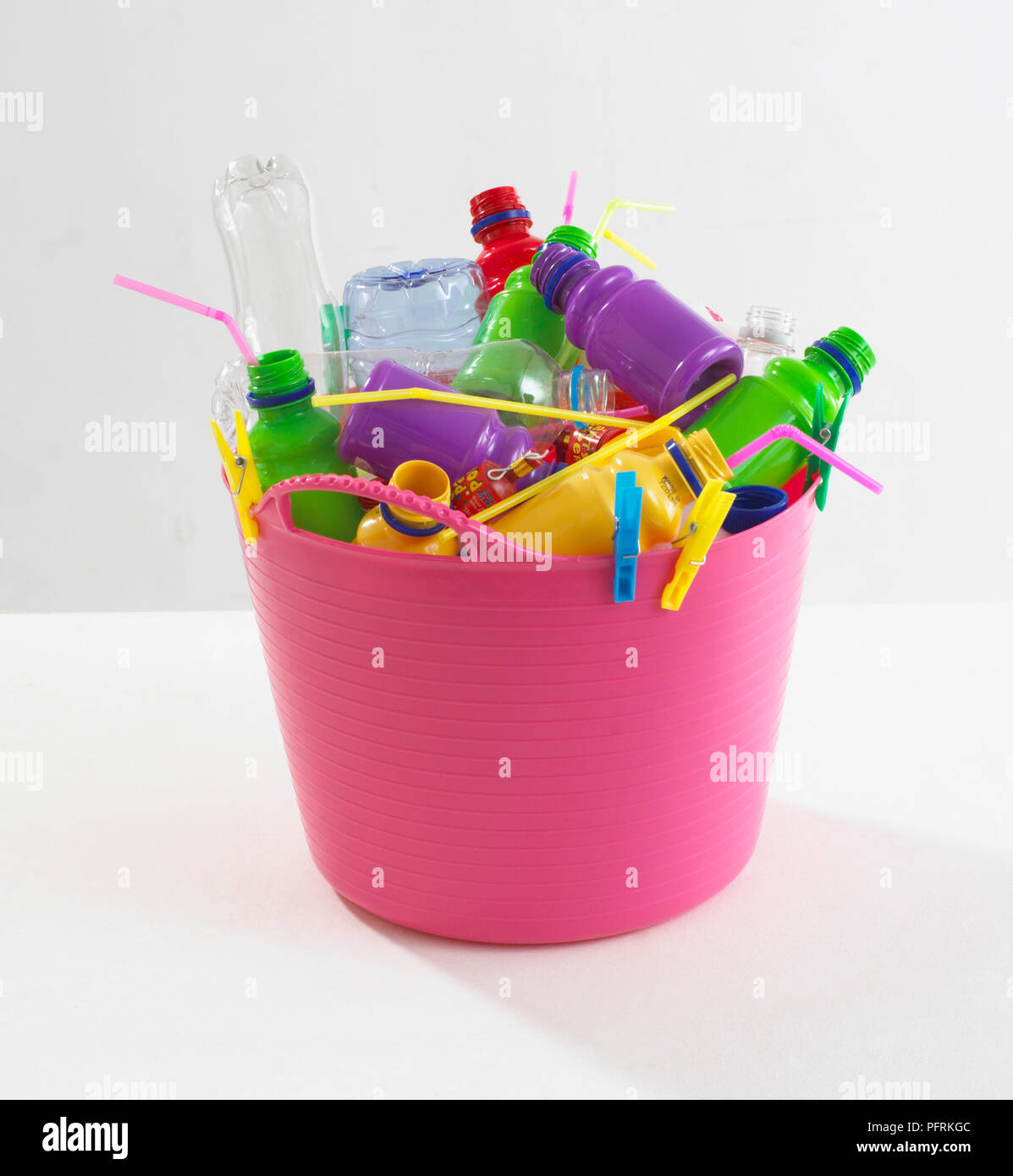 Plastic pink basket full of coloured plastic objects such as bottles ...