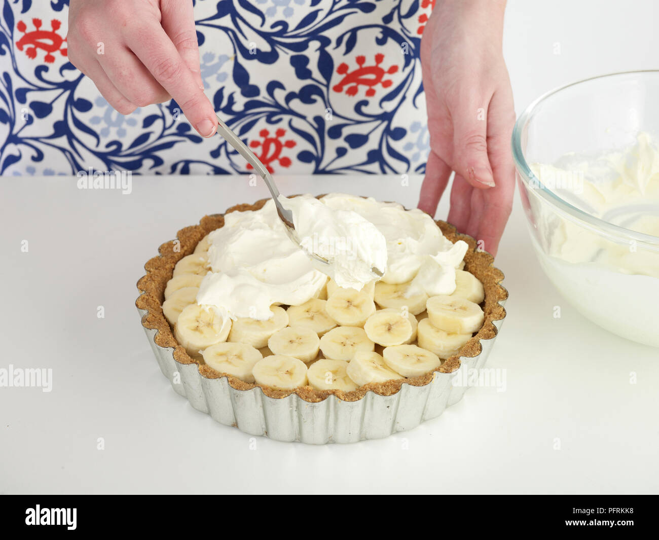Making banoffee pie, spreading whipped cream over banana slices Stock ...