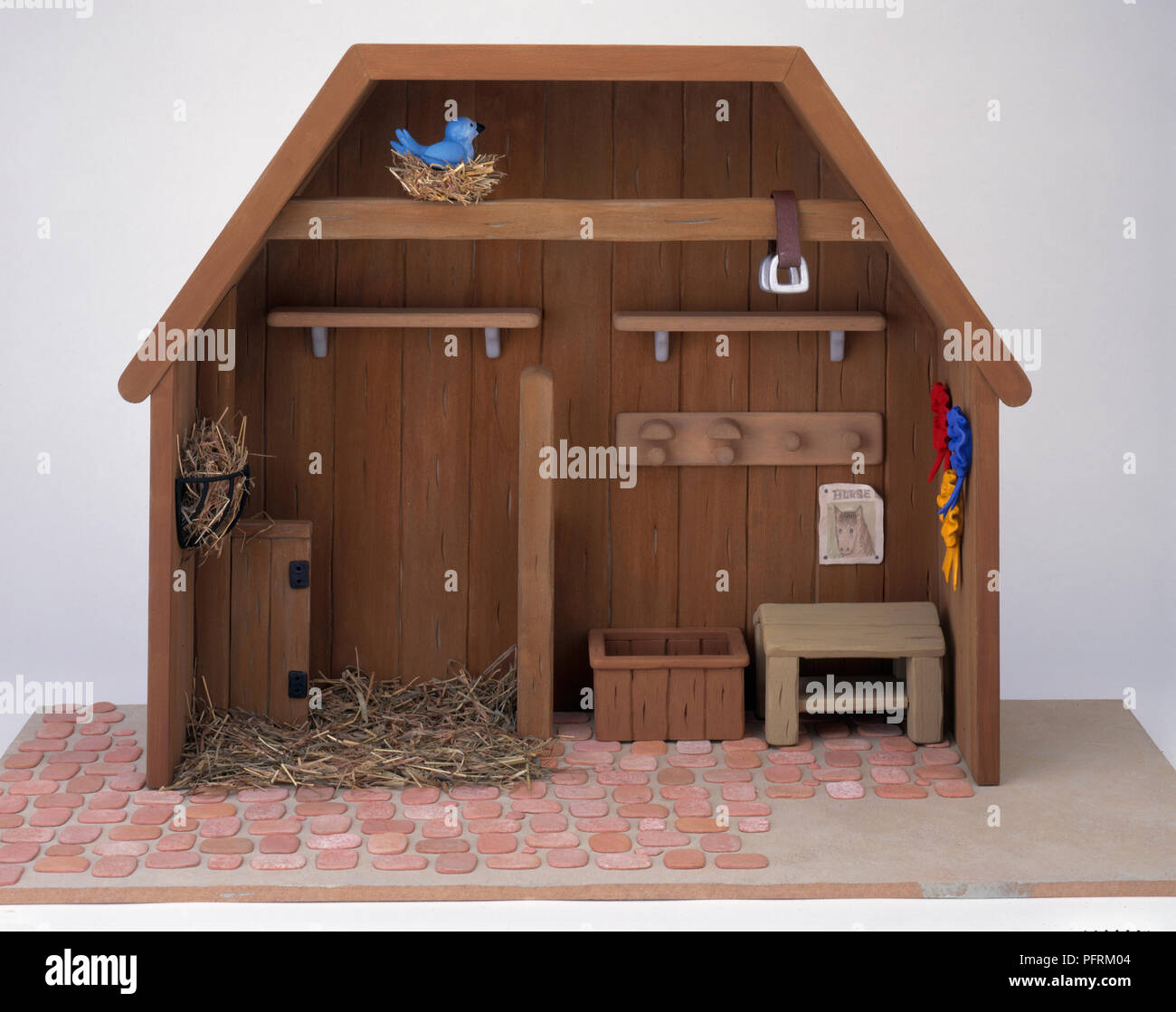 Cross section of toy stable with straw, rosettes and bird on nest ...