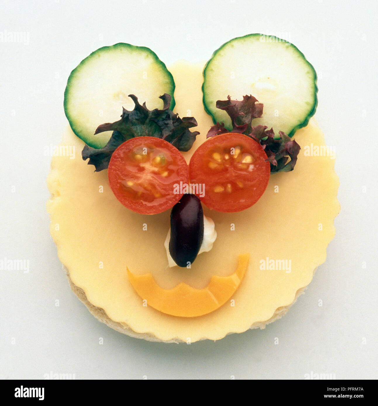 Face made from food using cheese covered muffin as a base, tomato eyes ...