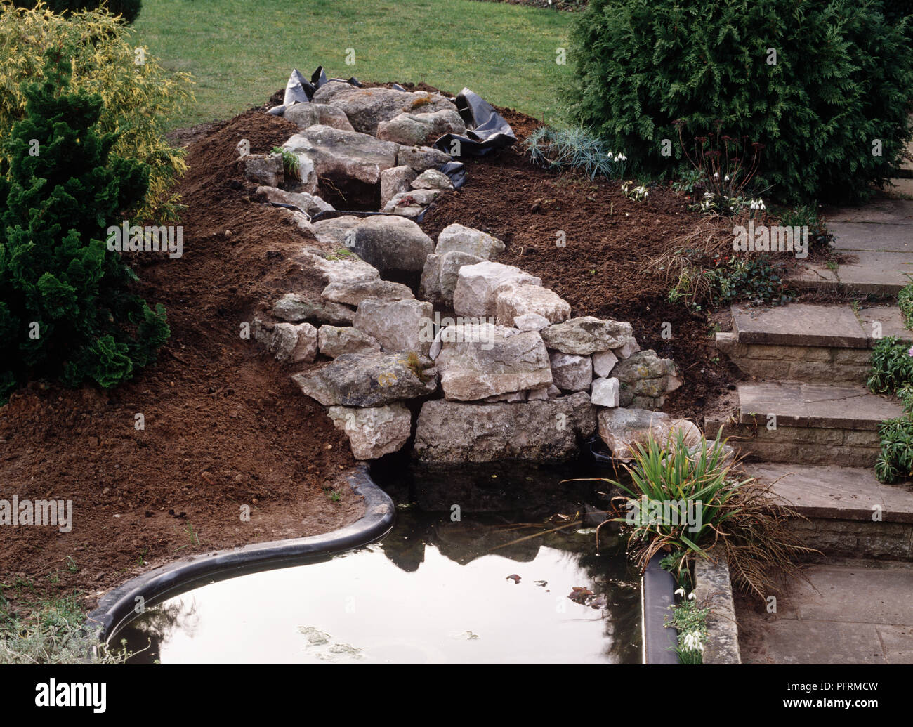 Using large rocks to construct stream above pond Stock Photo - Alamy
