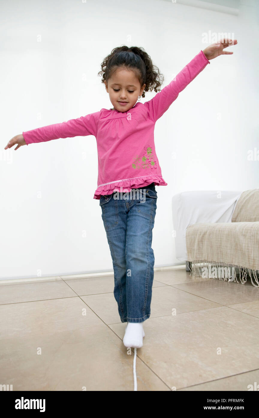 Girl walking along string line on floor, raising arms Stock Photo - Alamy
