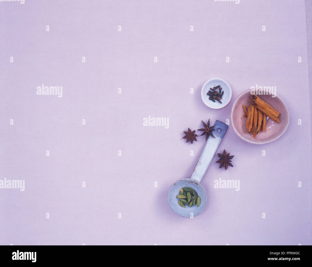 Star anise, cardamom pods, cloves and cinnamon in bowls, on spoon and ...