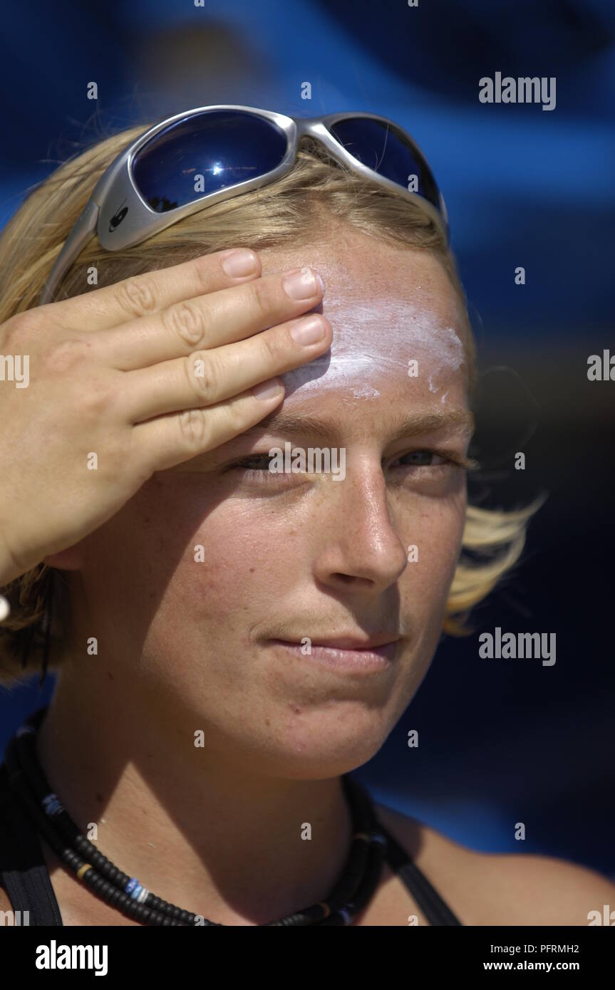 Young woman putting suncream on forehead Stock Photo - Alamy