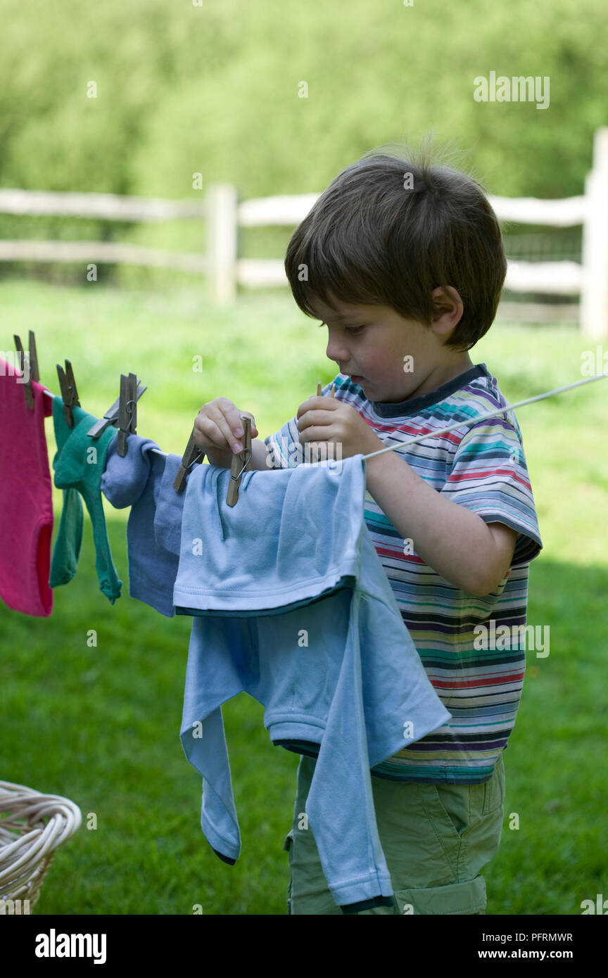 Boy hanging washing onto an outdoor line using wooden pegs Stock Photo ...