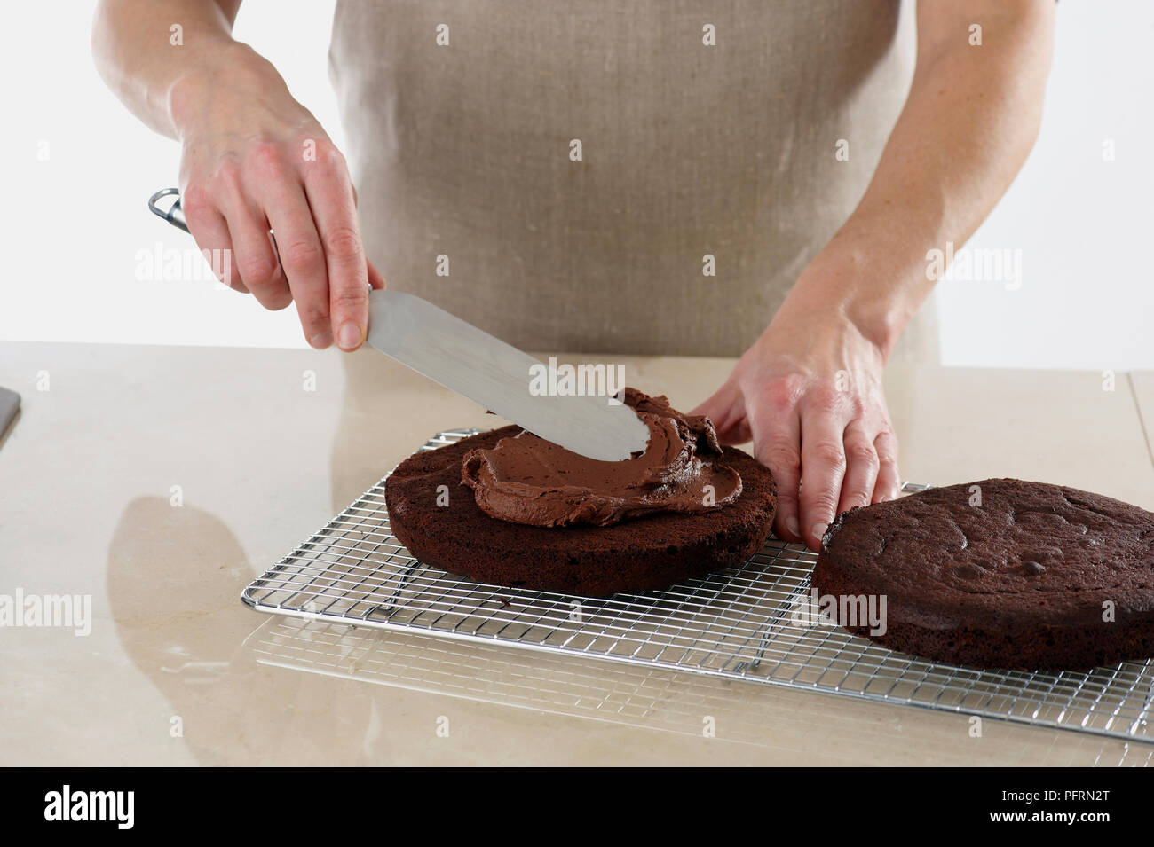 Spreading buttercream filling on bottom half of chocolate cake Stock ...