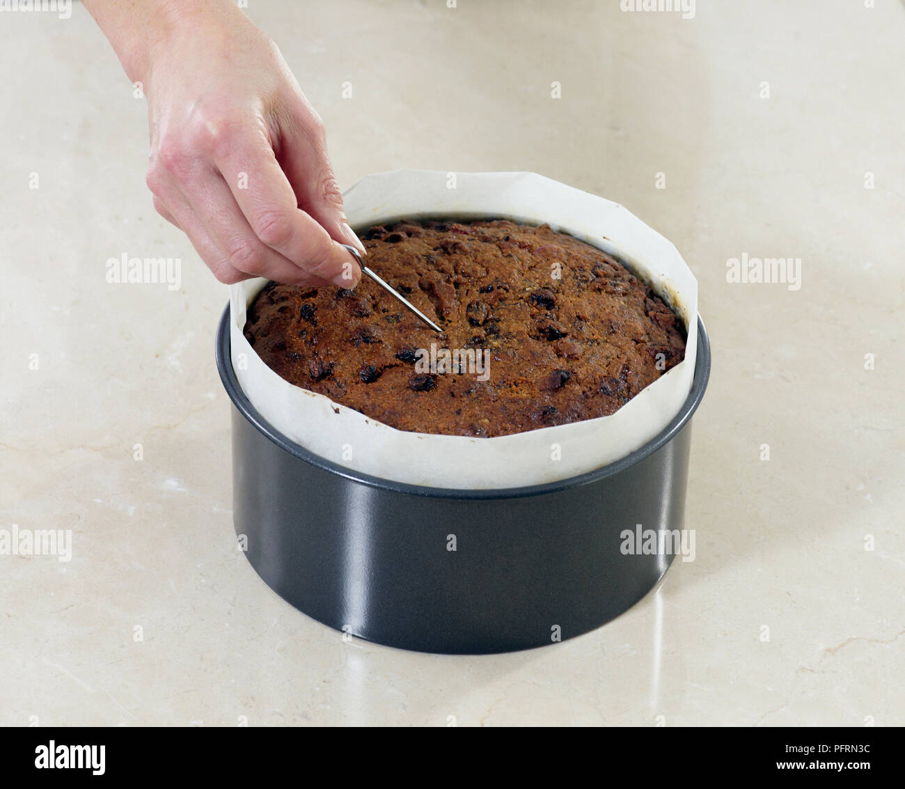 Testing fruit cake by inserting a skewer Stock Photo - Alamy