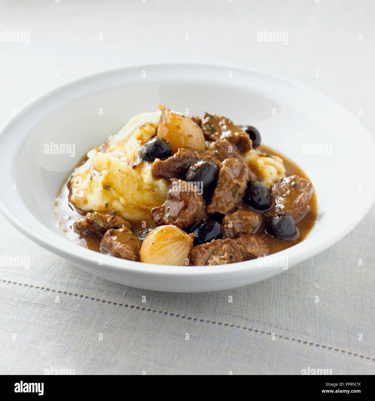 Beef stew with black olives, small onions and mashed potato served in ...