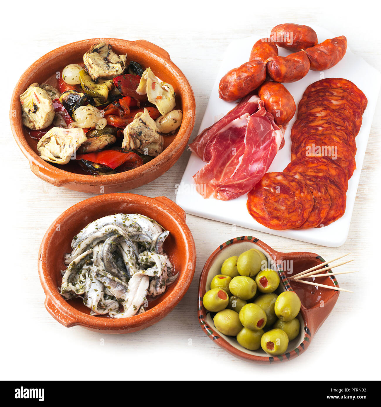Selection of tapas in traditional Spanish-style clay bowls and on white ...