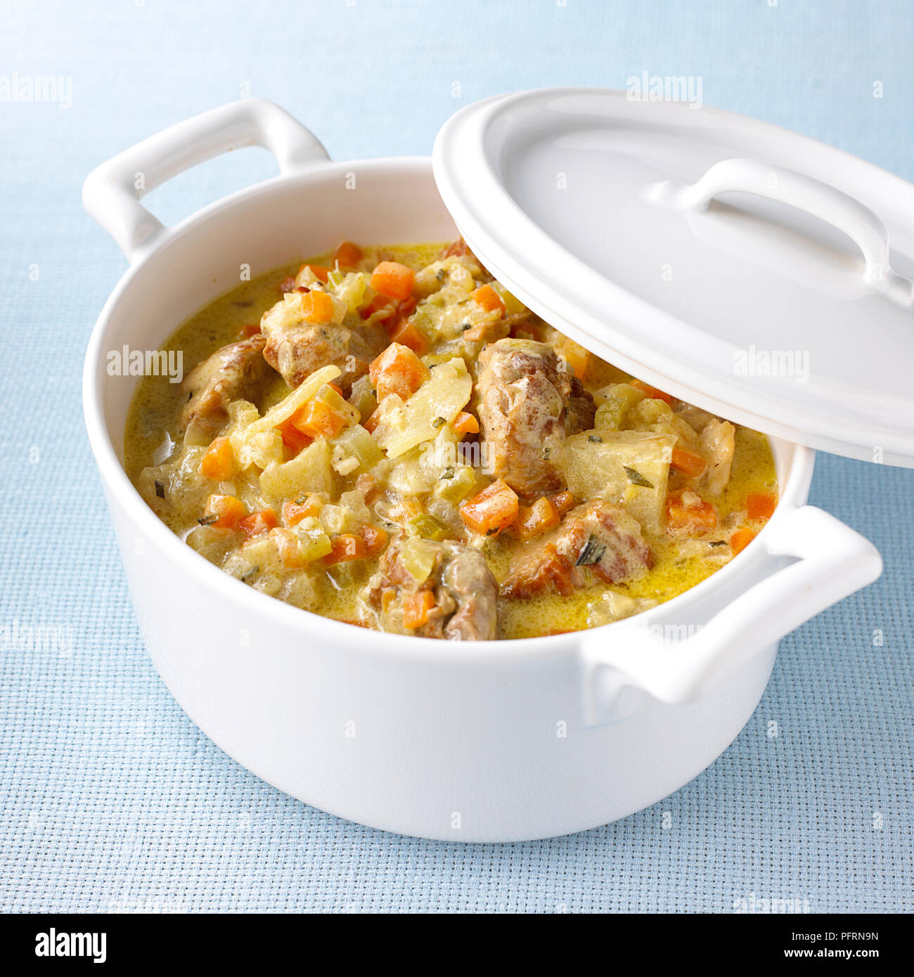 Pork Normandy in white casserole dish on blue tablecloth, close-up ...