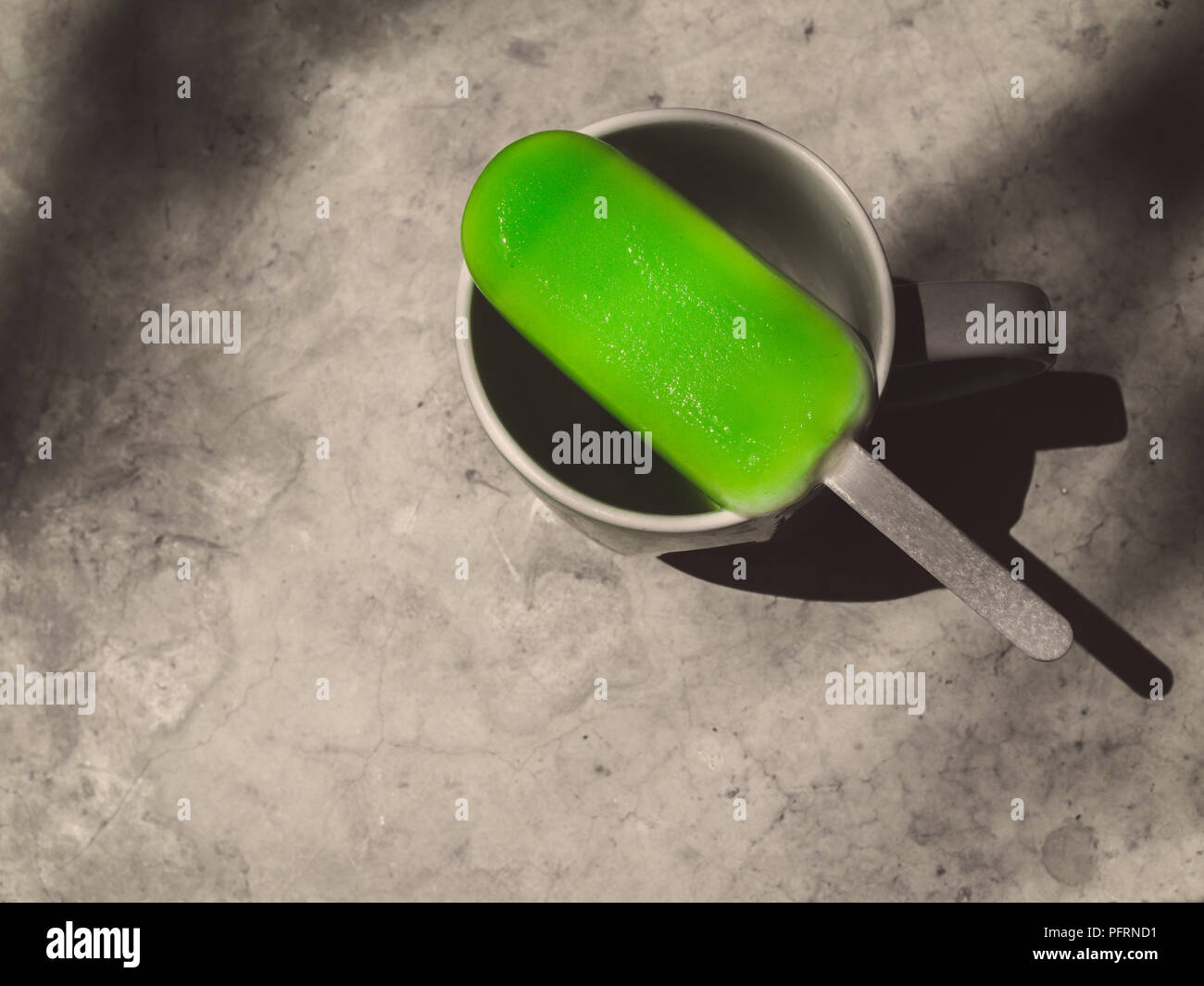 Green Popsicle Ice Pop on Ceramic Glass with Light and Shadow on Cement ...