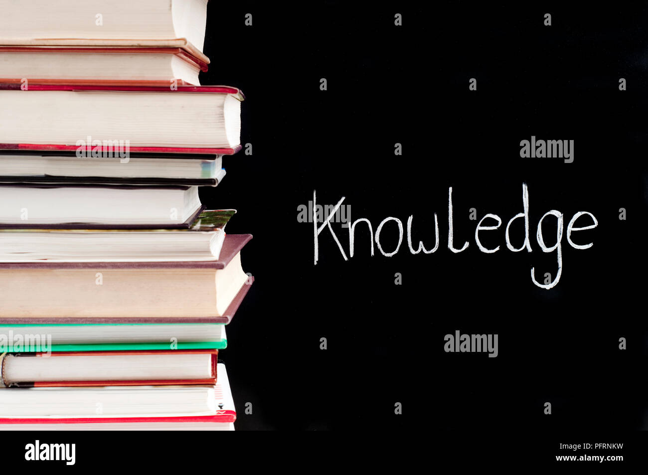 The word 'Knowledge' written in chalk on a blackboard, next to a pile ...