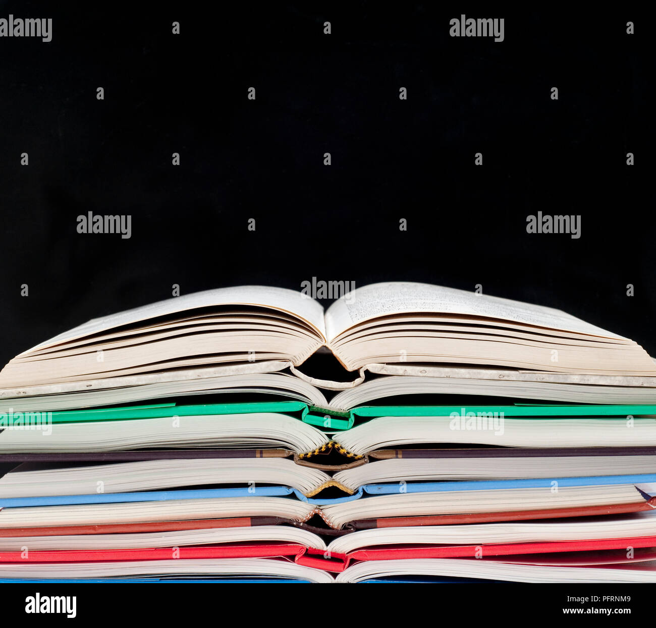 Stack of open hardback books, against black background Stock Photo - Alamy