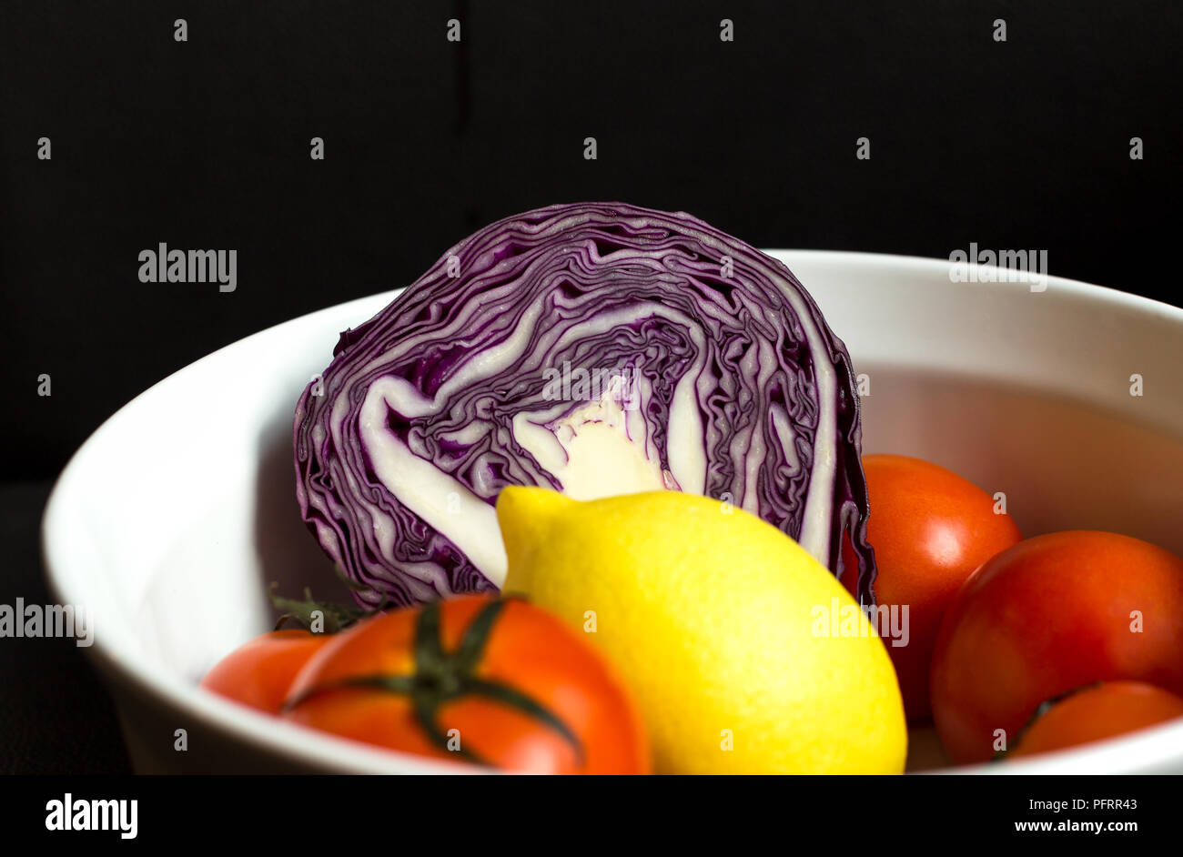 Red cabbage cut in half in white bowl with lemon and tomato isol Stock ...