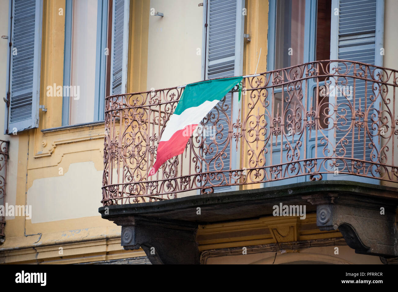 Italy, Piedmont, Alba, iron balcony with Italian flag draped over ...