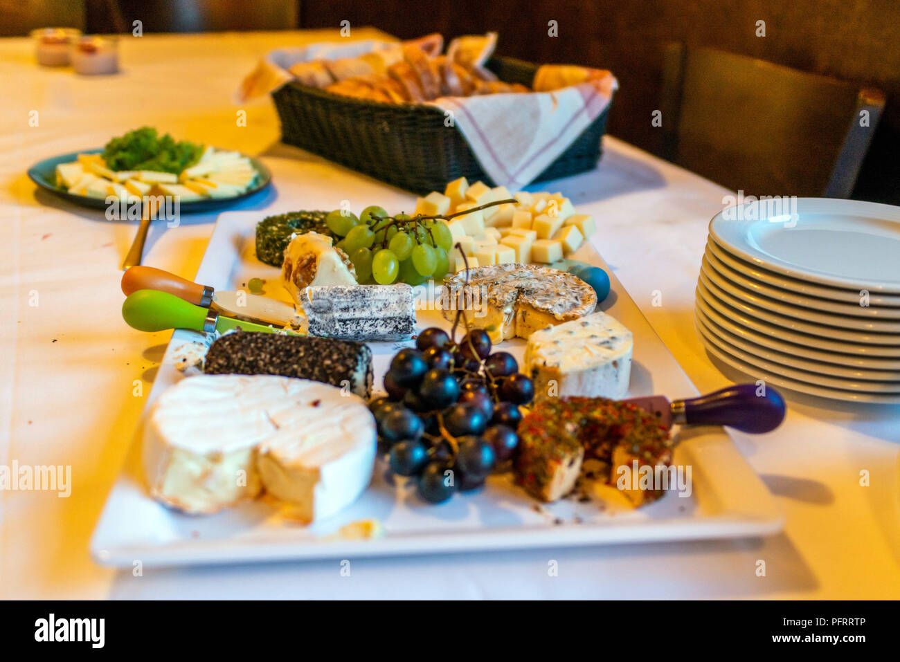 Cheese plate. Variety of cheese sorts with grapes and buffet table with ...