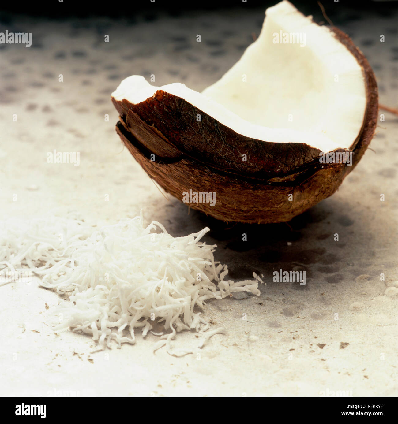Broken coconut shell showing white meat, next to heap of grated coconut ...